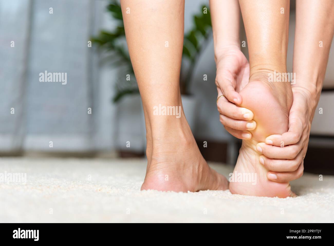 Foot pain, Asian woman standing feeling pain in her foot at home ...