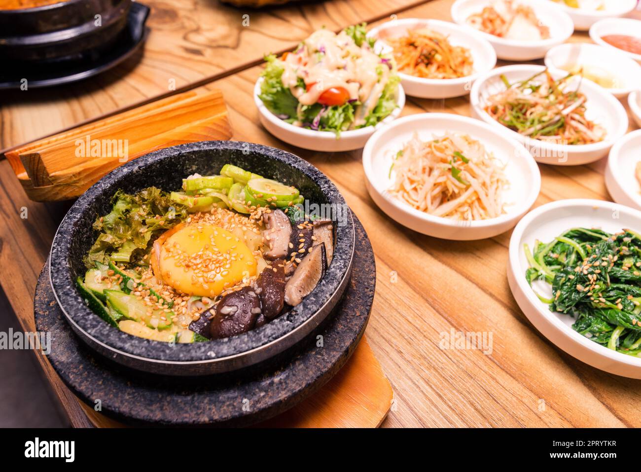 Bibimbap in a black heated stone bowl, Korean traditional dish- bibimbap mixed rice with ...