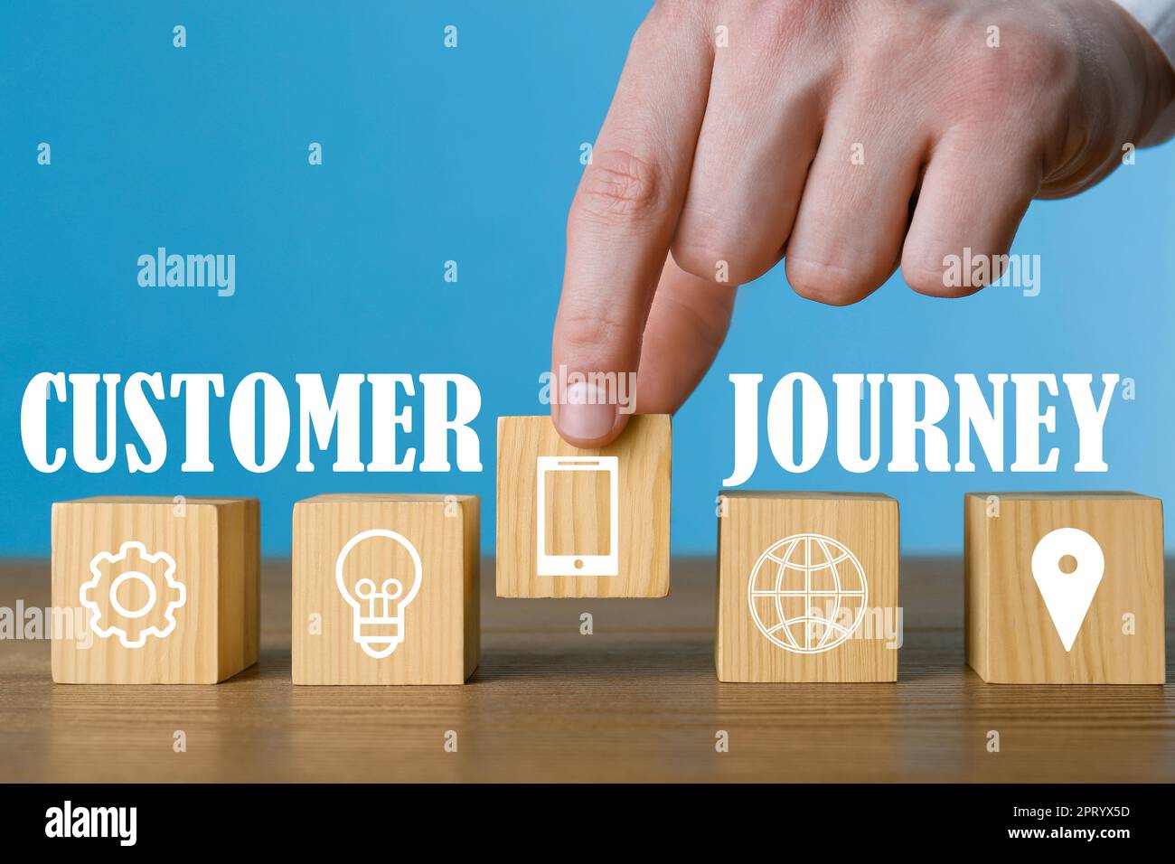 Man arranging cubes with different images in row on wooden table ...