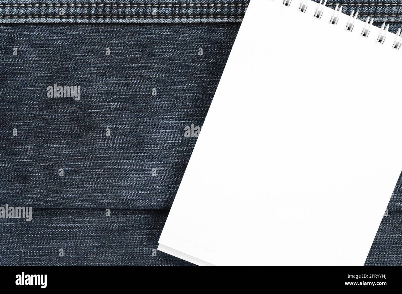 White notebook with clean pages lying on dark blue jeans background ...
