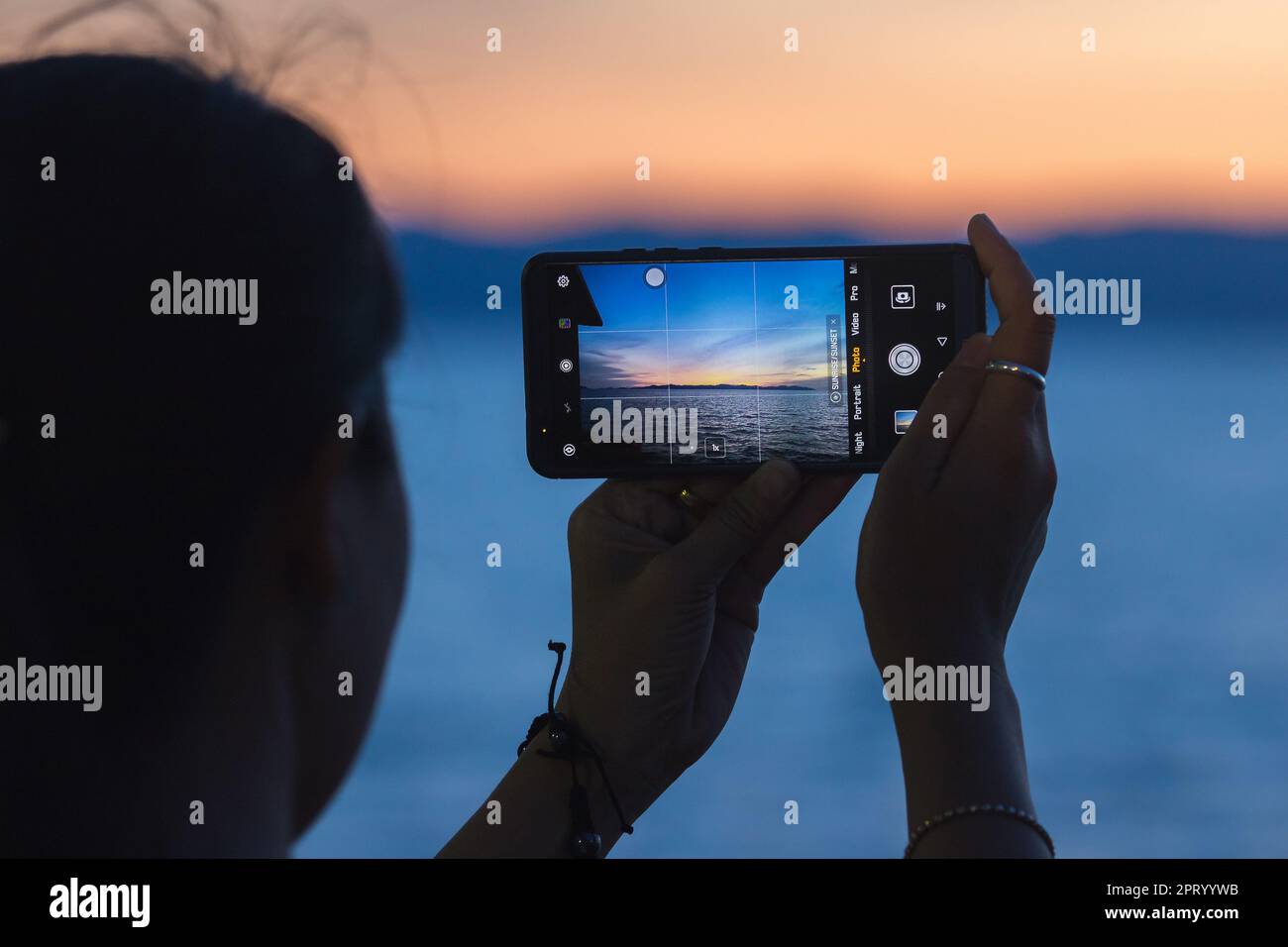 The picture of the beautiful sunset in the sea on the phone Stock Photo ...