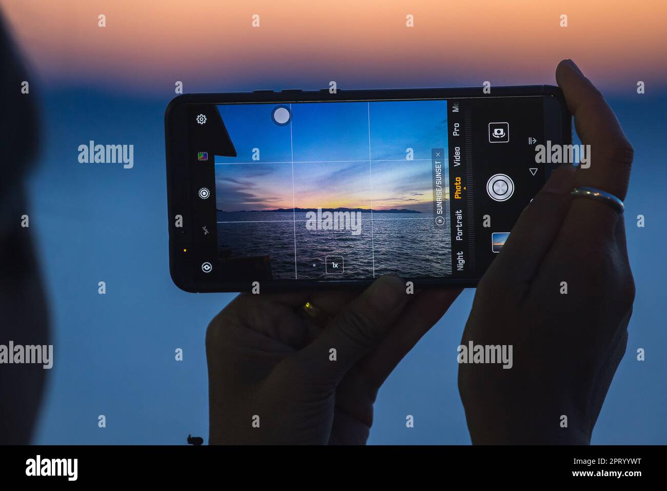 The picture of the beautiful sunset in the sea on the phone Stock Photo ...