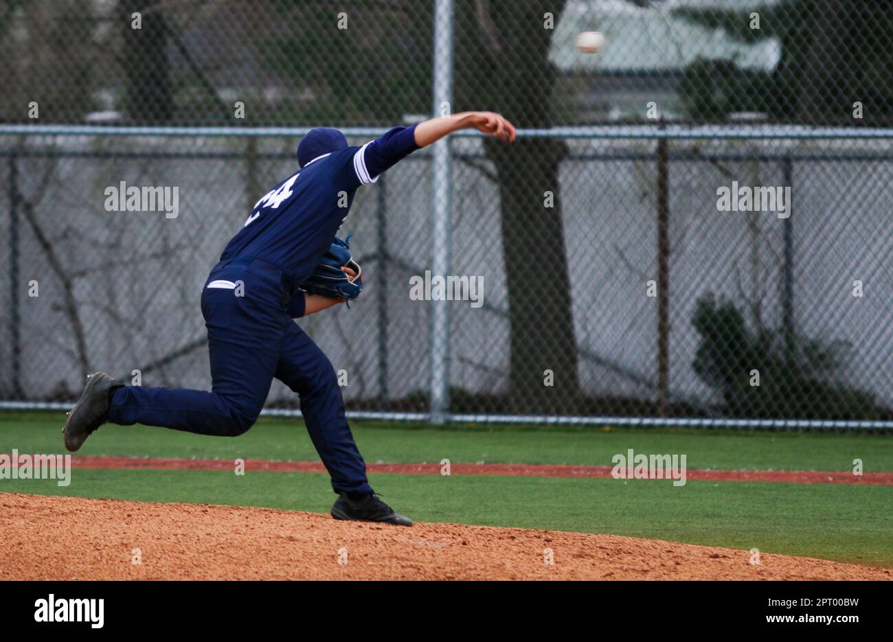 Side view of a high school pitcher releasing the ball pitching to home ...