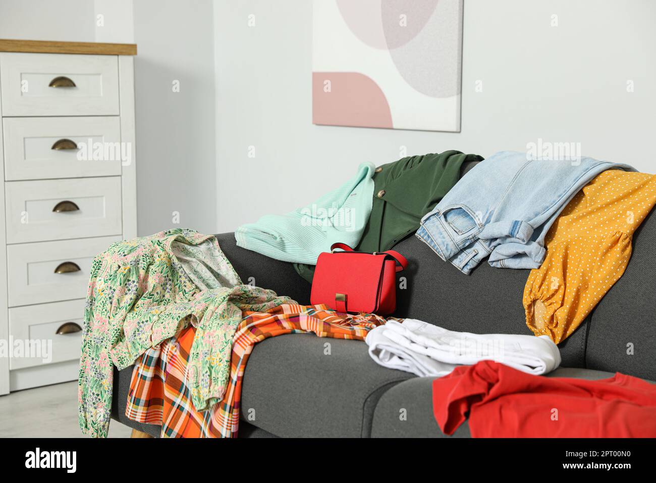 Messy pile of clothes on sofa in living room Stock Photo - Alamy