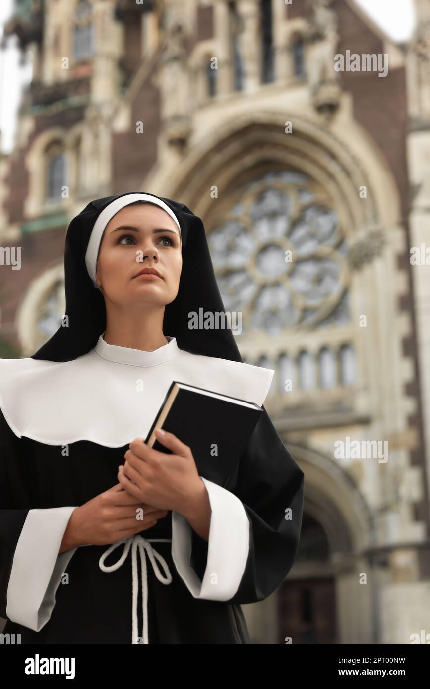 Young nun with Bible near cathedral outdoors Stock Photo - Alamy