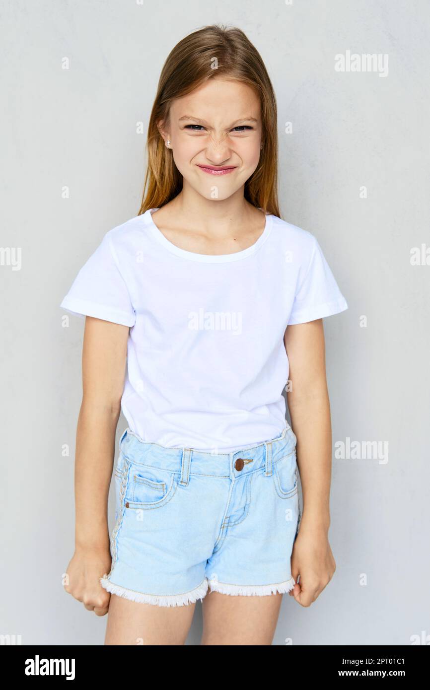 Young angry and mischievous girl in white t-shirt and jeans shorts ...