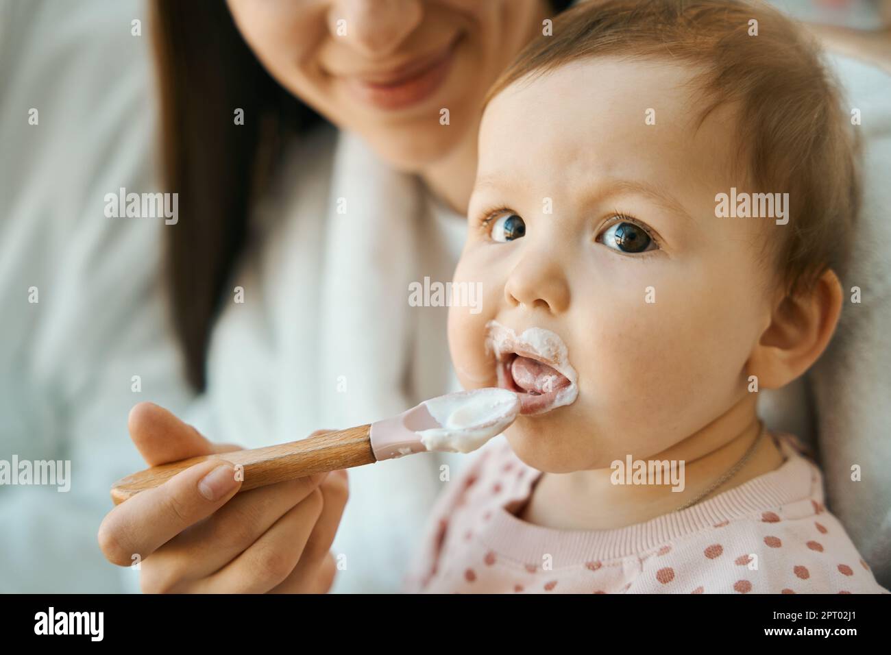 Smiling woman feeding a small child with a small spoon Stock Photo - Alamy