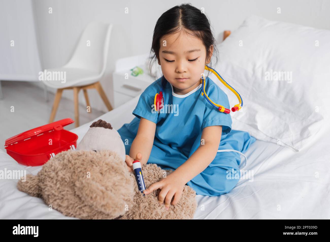 asian child in hospital gown doing injection to teddy bear with toy ...