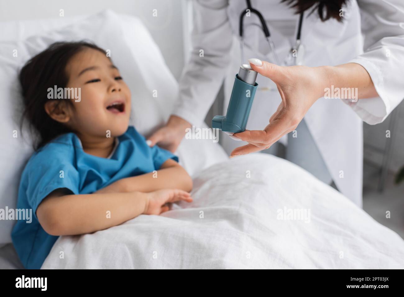 blurred pediatrician holding inhaler near asian child opening mouth on ...
