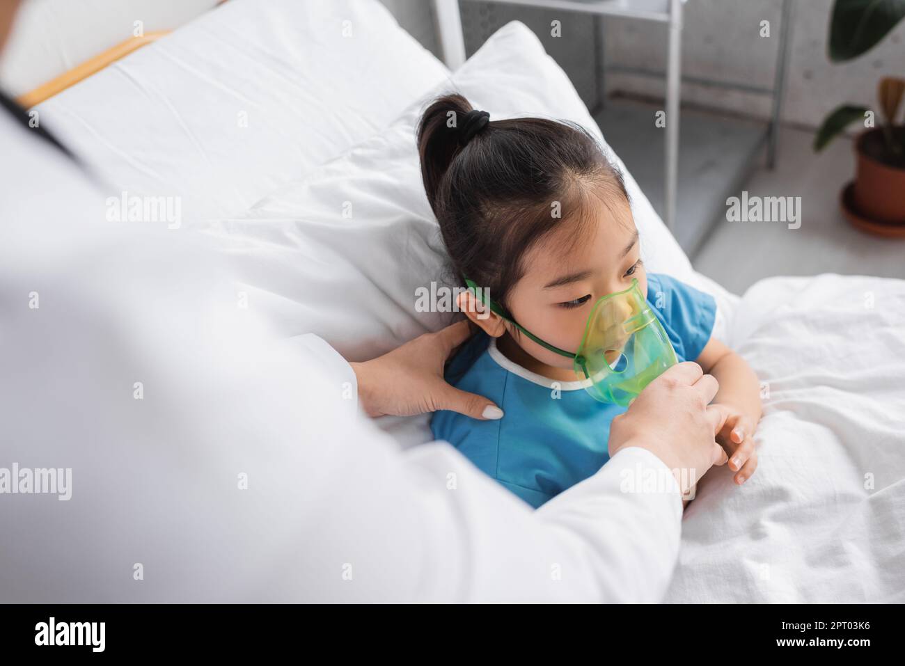 blurred doctor adjusting oxygen mask on sick asian child on hospital ...