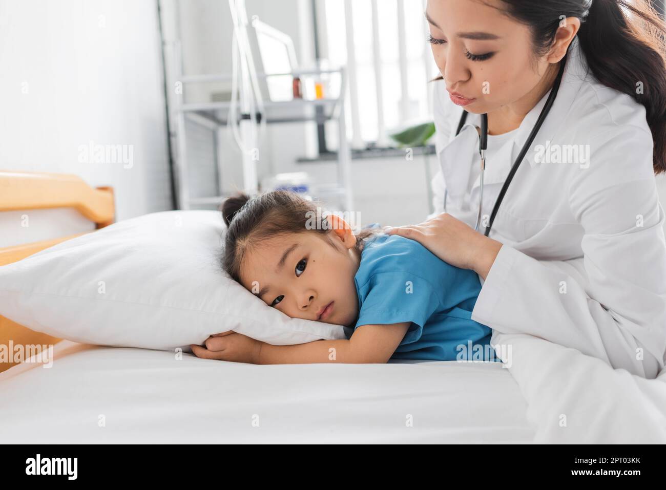 young asian doctor calming sad child lying on bed in clinic,stock image ...