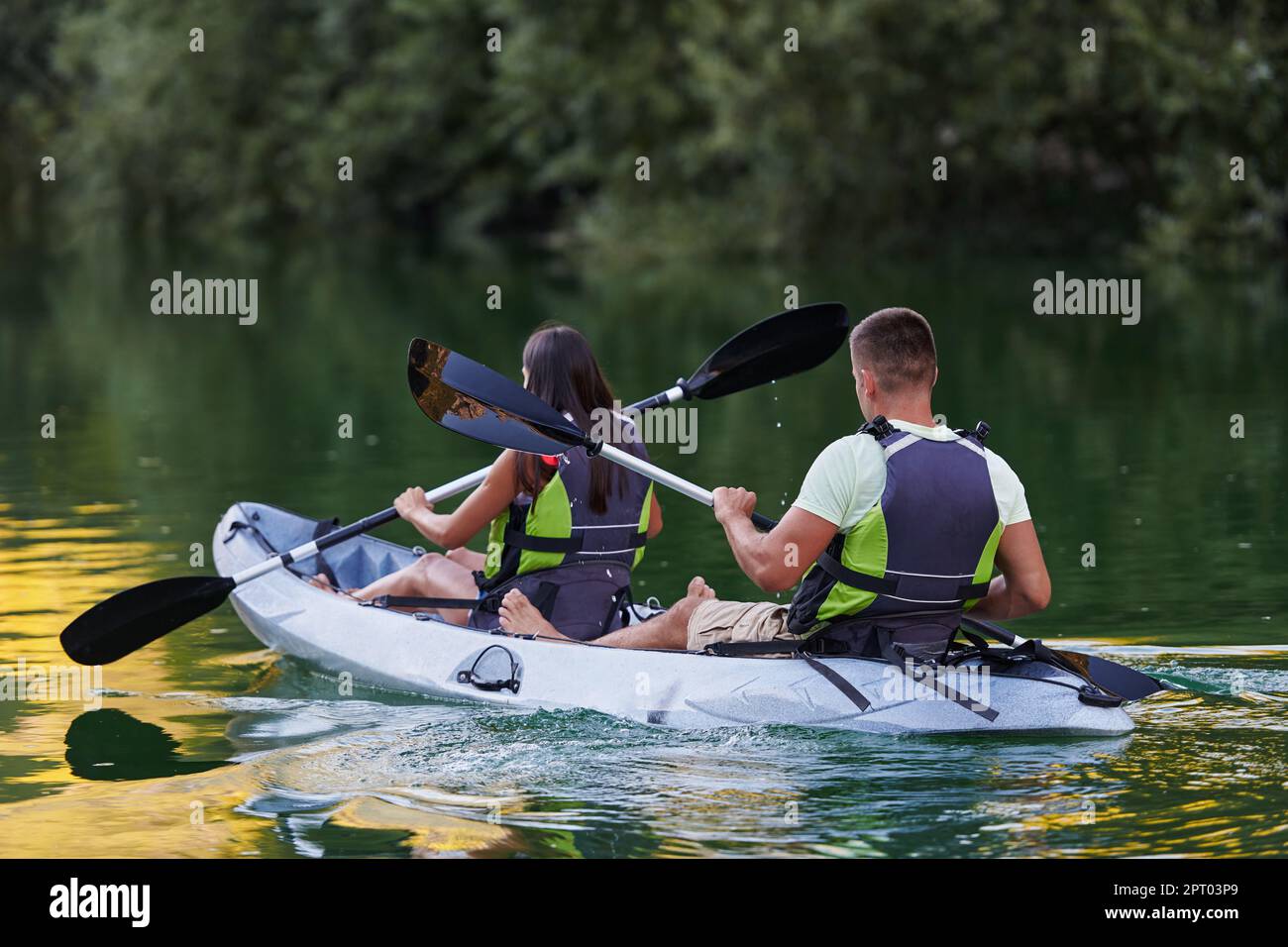 A young couple enjoying an idyllic kayak ride in the middle of a ...