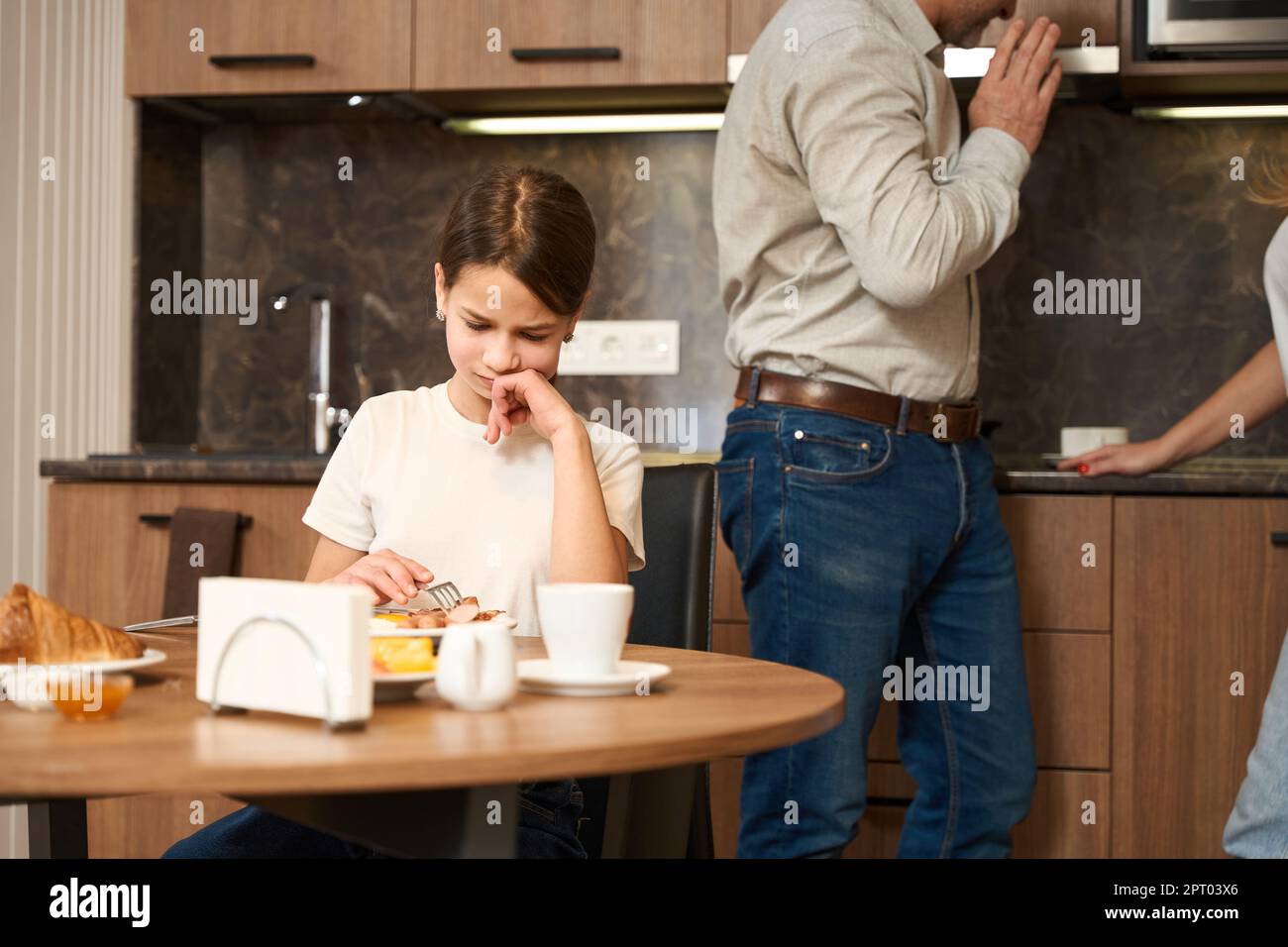 Sad little girl having breakfast in the kitchen Stock Photo - Alamy