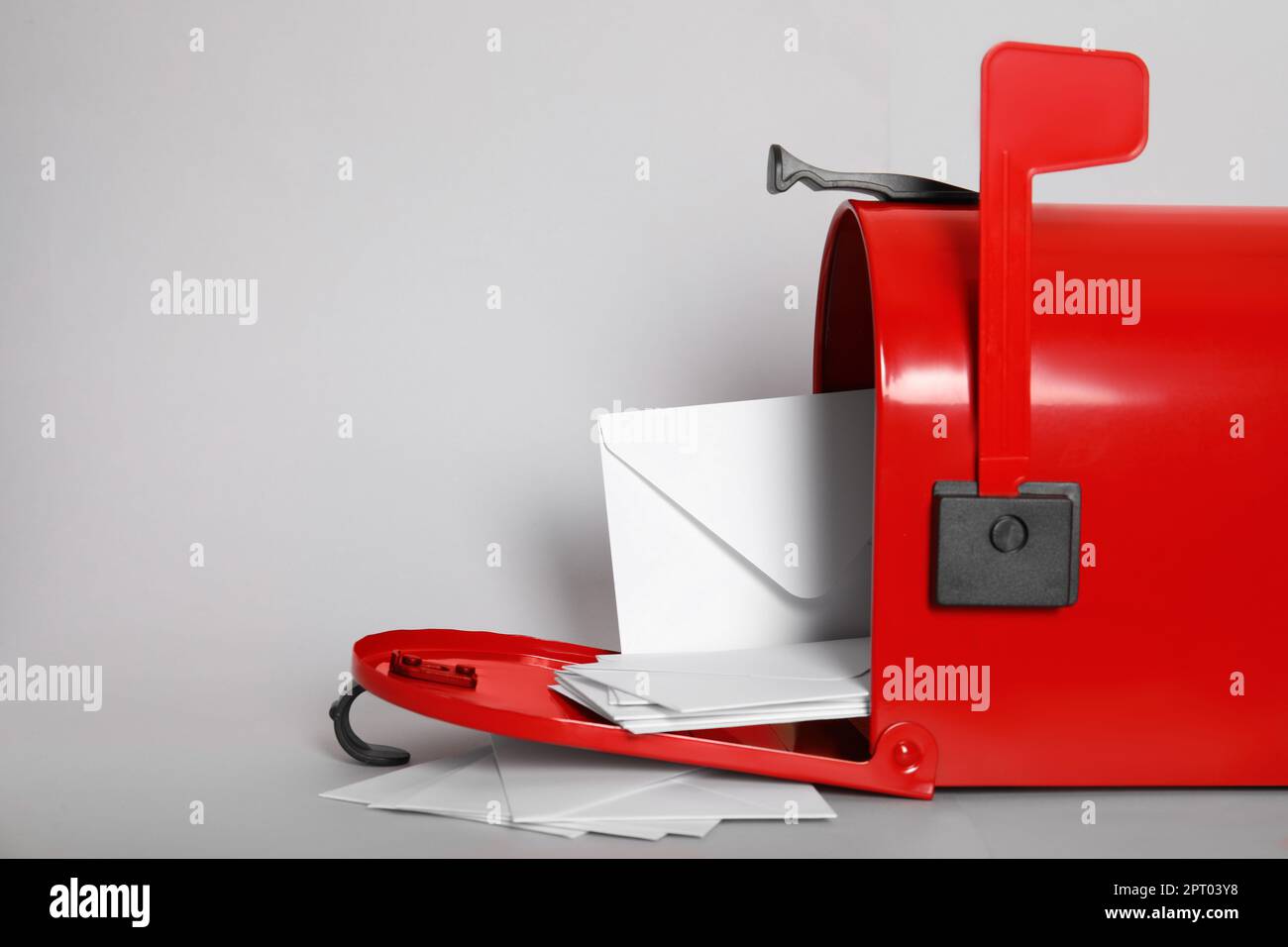 Open red letter box with envelopes on light background, closeup. Space ...