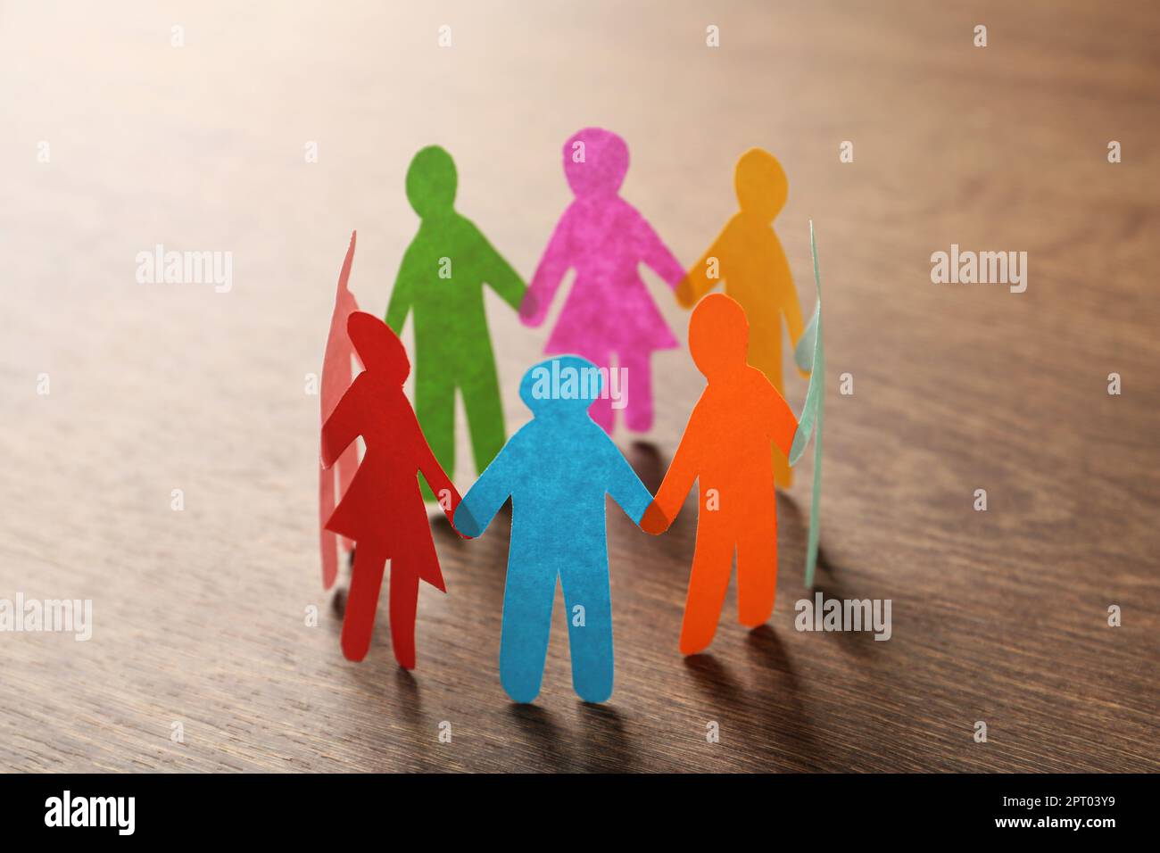 Many different paper human figures standing in circle on wooden table ...