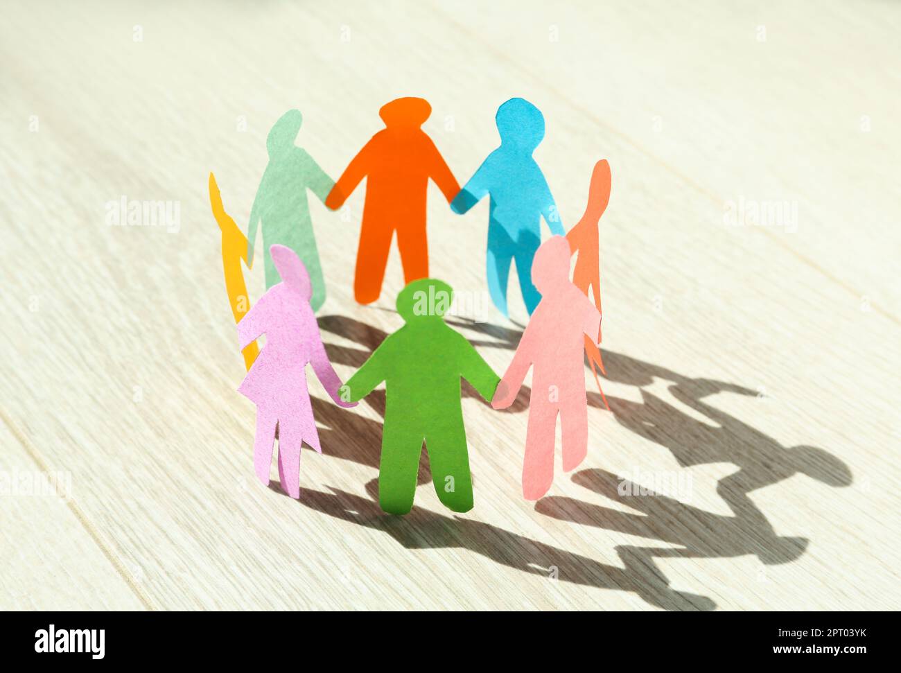 Many different paper human figures standing in circle on white wooden ...