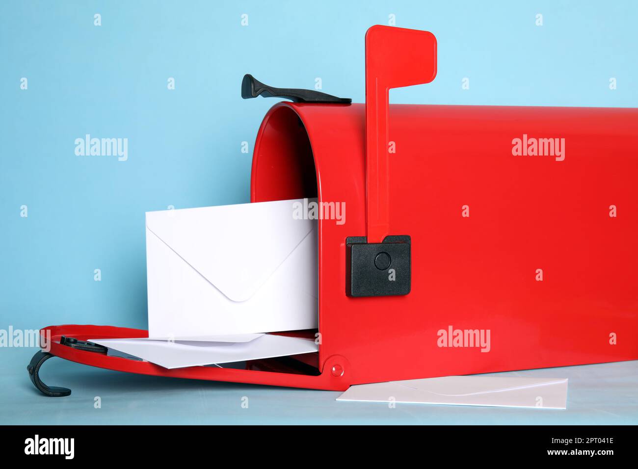 Open red letter box with envelopes on turquoise background, closeup ...