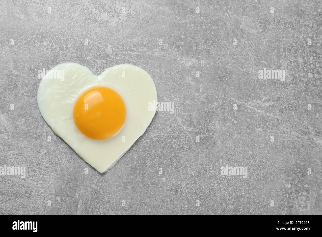 Heart shaped fried egg on light grey table, top view Stock Photo - Alamy