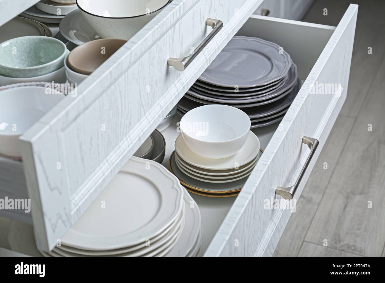 Open drawers with different plates and bowls in kitchen, closeup Stock ...