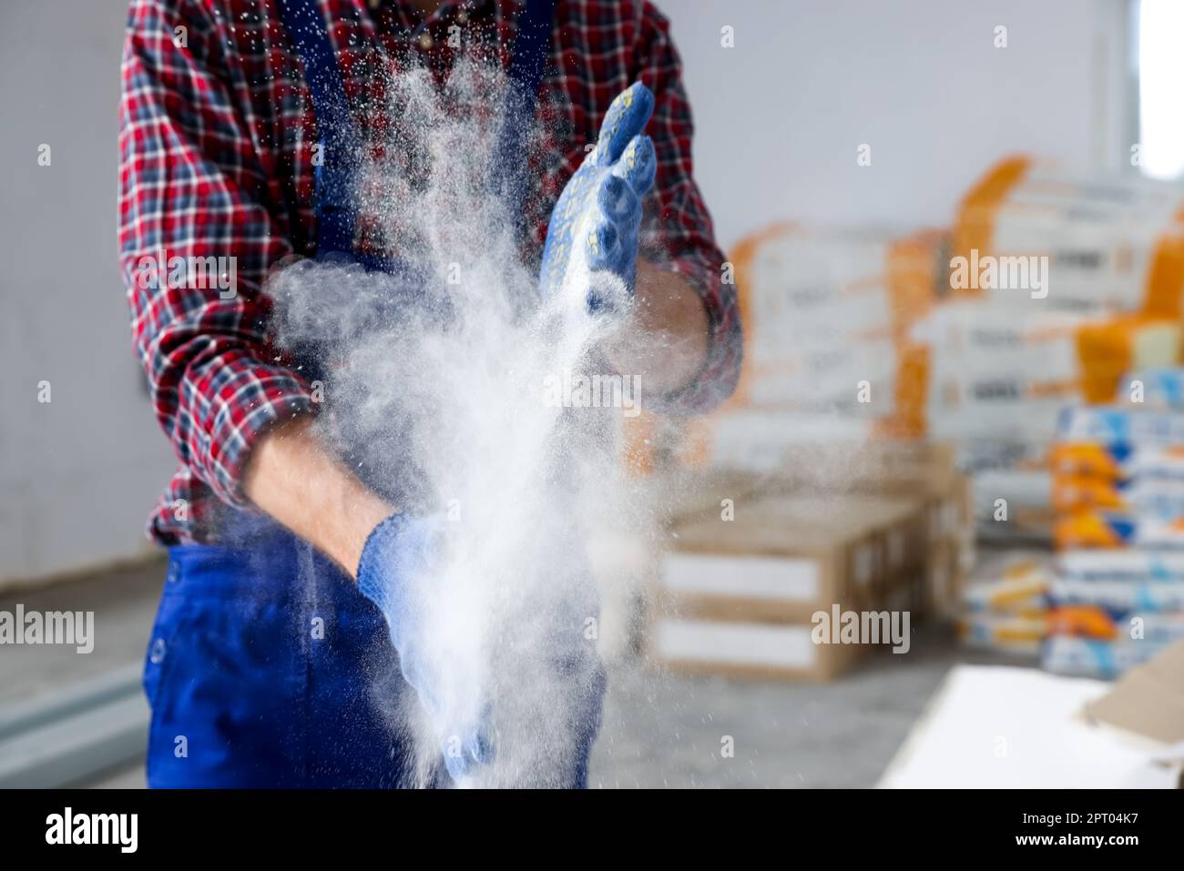 Construction worker shaking off dust from hands in room prepared for ...