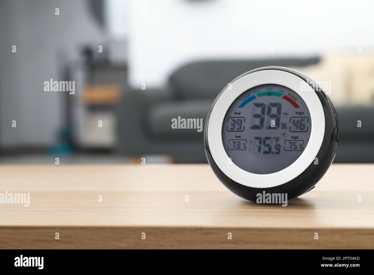 Digital hygrometer with thermometer on wooden table in room. Space for ...