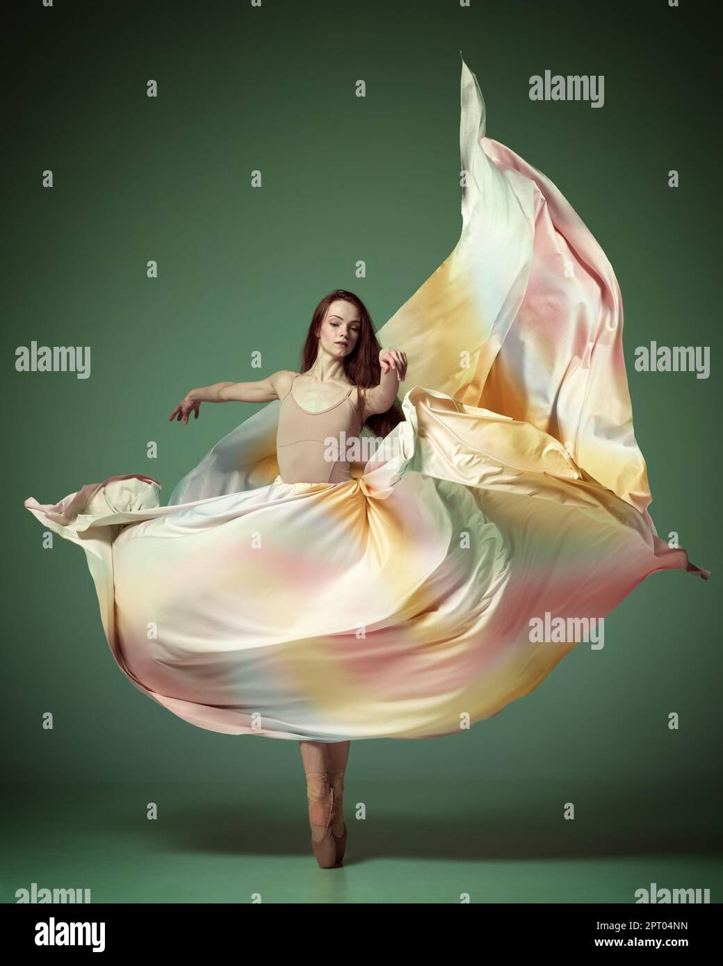 Portrait with one young girl, beautiful ballerina wearing silk dress spinning in dance over dark ...