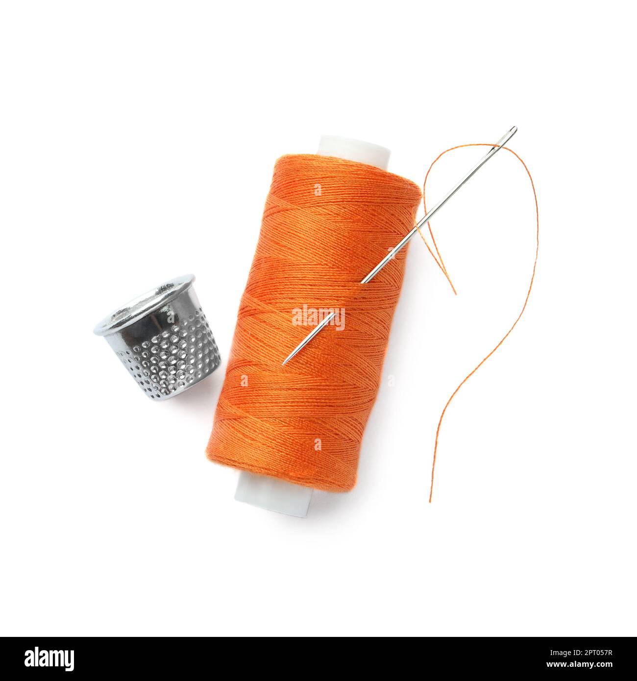 Spool of orange sewing thread with needle and thimble on white ...