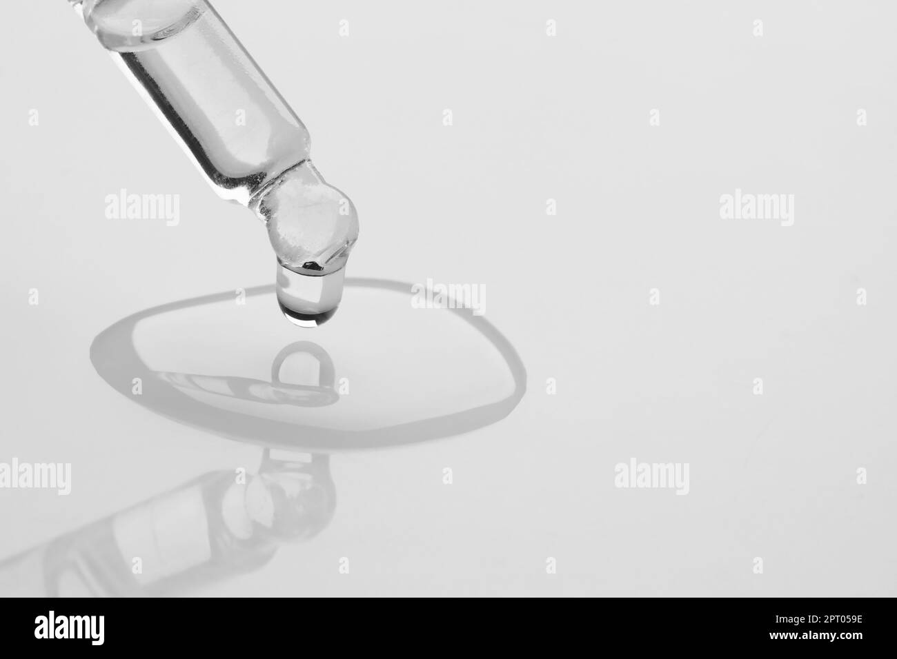 Dripping face serum from pipette on white background, closeup. Space ...