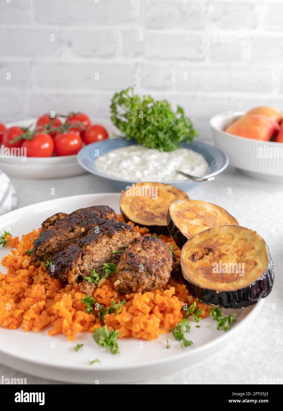 Greek bifteki with feta cheese, tomato rice and fried eggplant on a ...