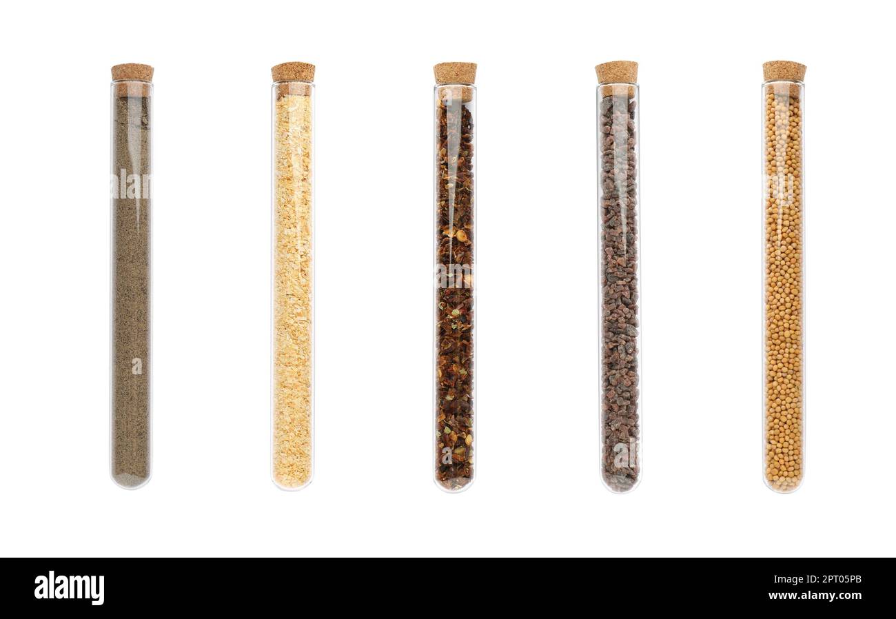 Set of glass tubes with different spices on white background, top view ...