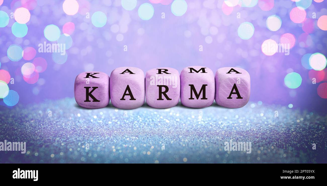 Wooden cxubes with word Karma on shiny glitter against violet ...
