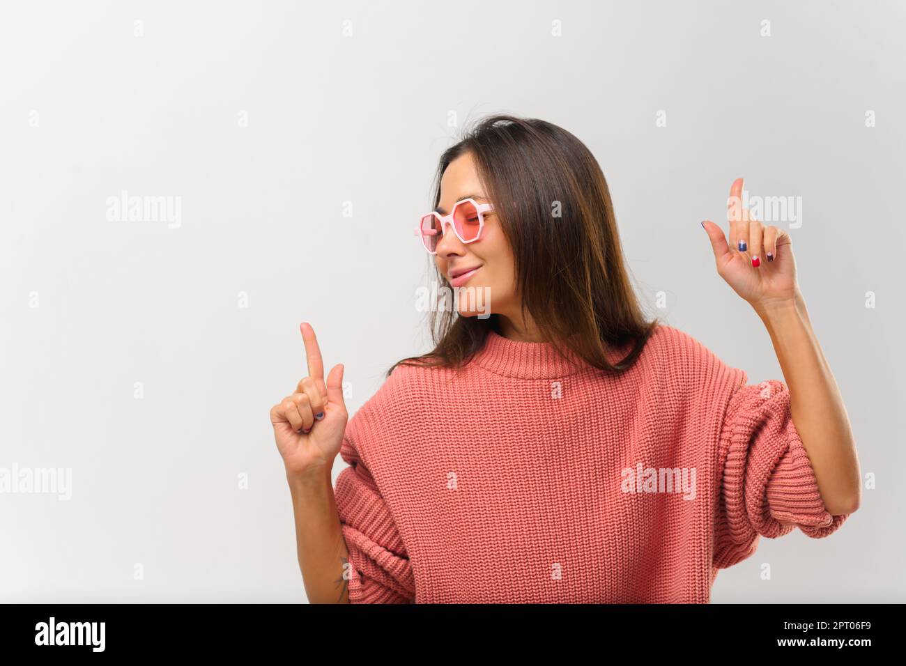 Victory concept. Joyful and cheerful curly brunette woman raising arms ...