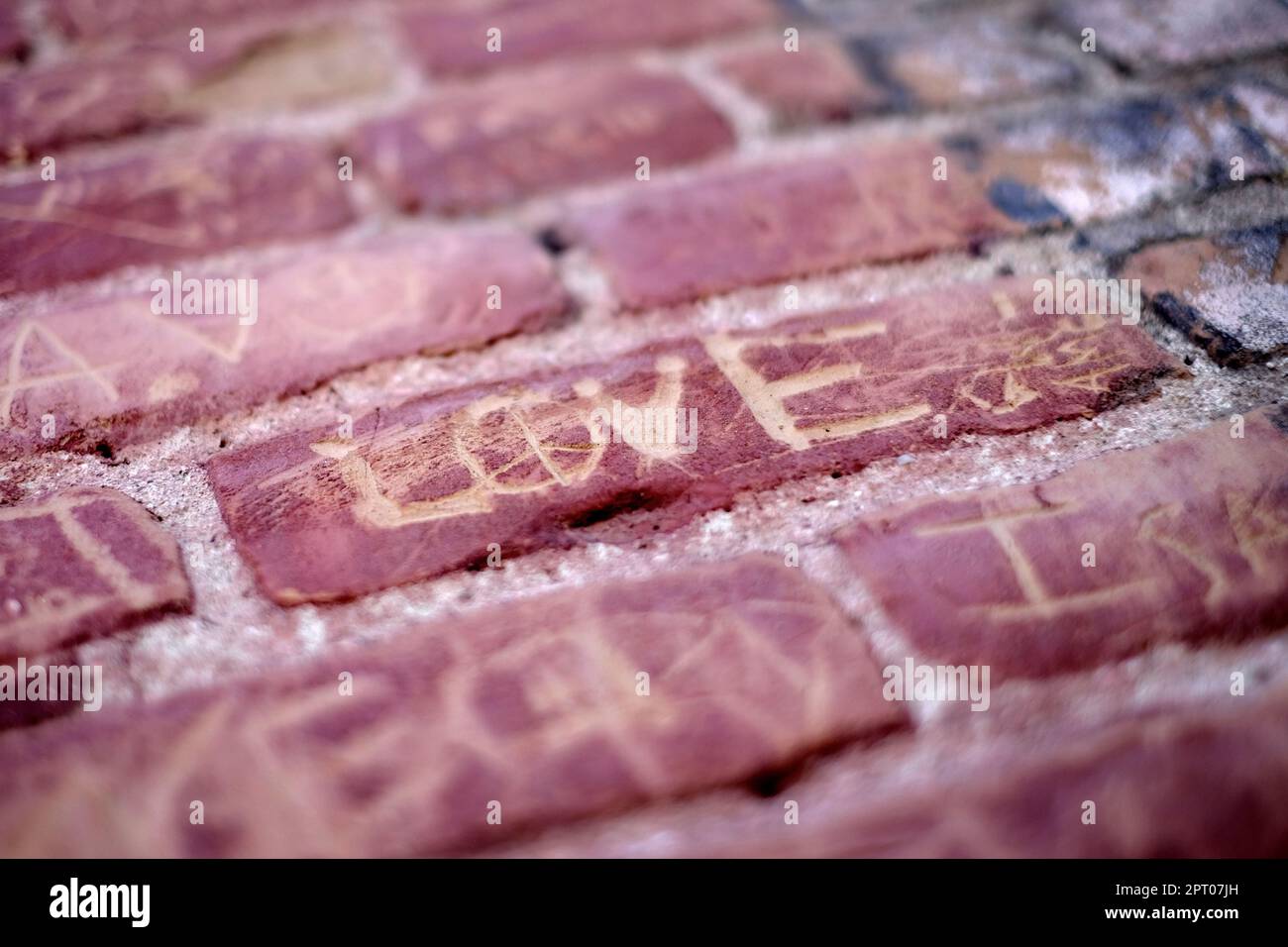 Love and symbol of affection scratched written on old brick wall Stock ...