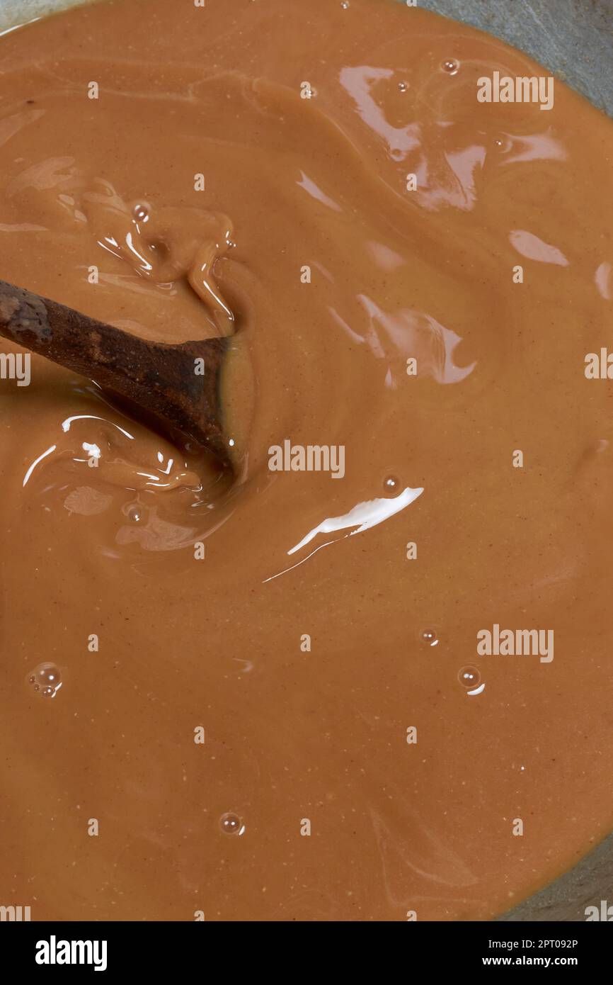 close-up of spoon mixing rice flour with coconut milk to make dodol ...