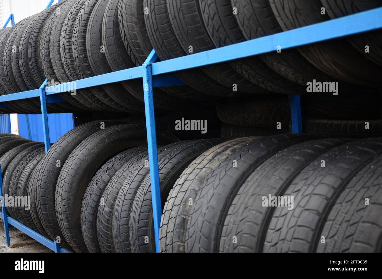 Rack with variety of car tires in automobile store. Many black tires. Tire stack background ...