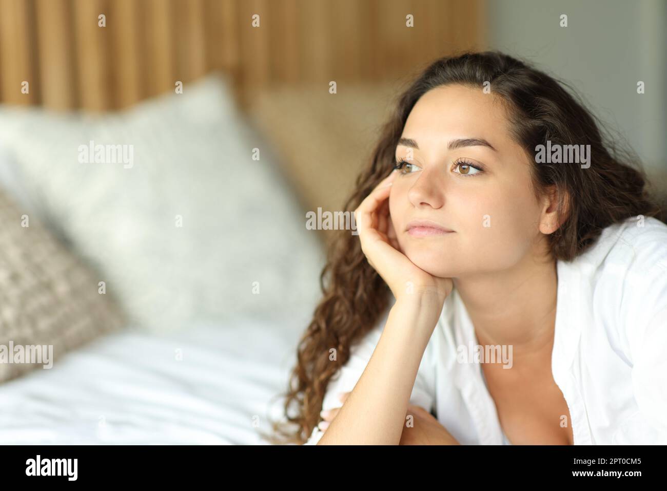 Pensive serious woman lying on a bed looking away in the bedroom Stock ...