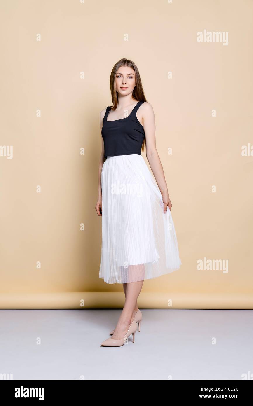 Full length portrait of pretty young woman in black tank top and white ...