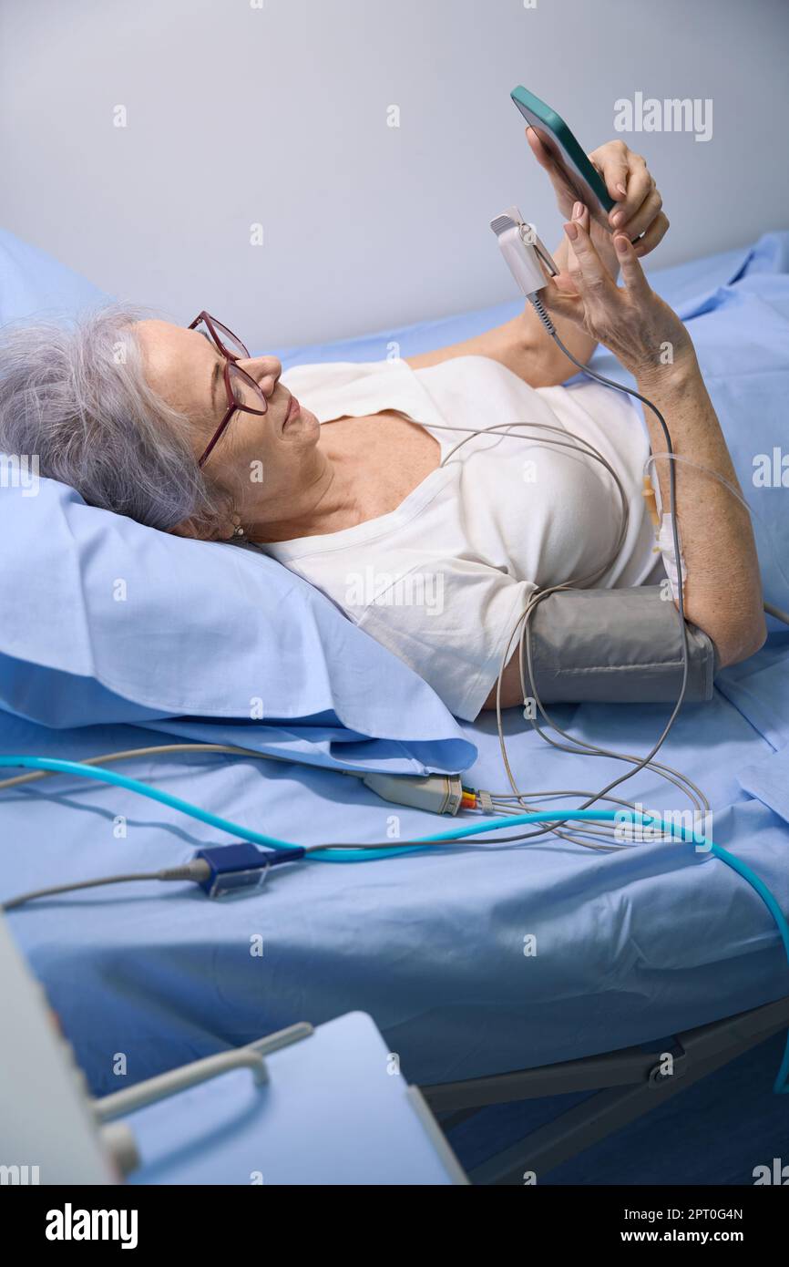 Elderly woman is chatting on mobile phone from hospital room Stock ...
