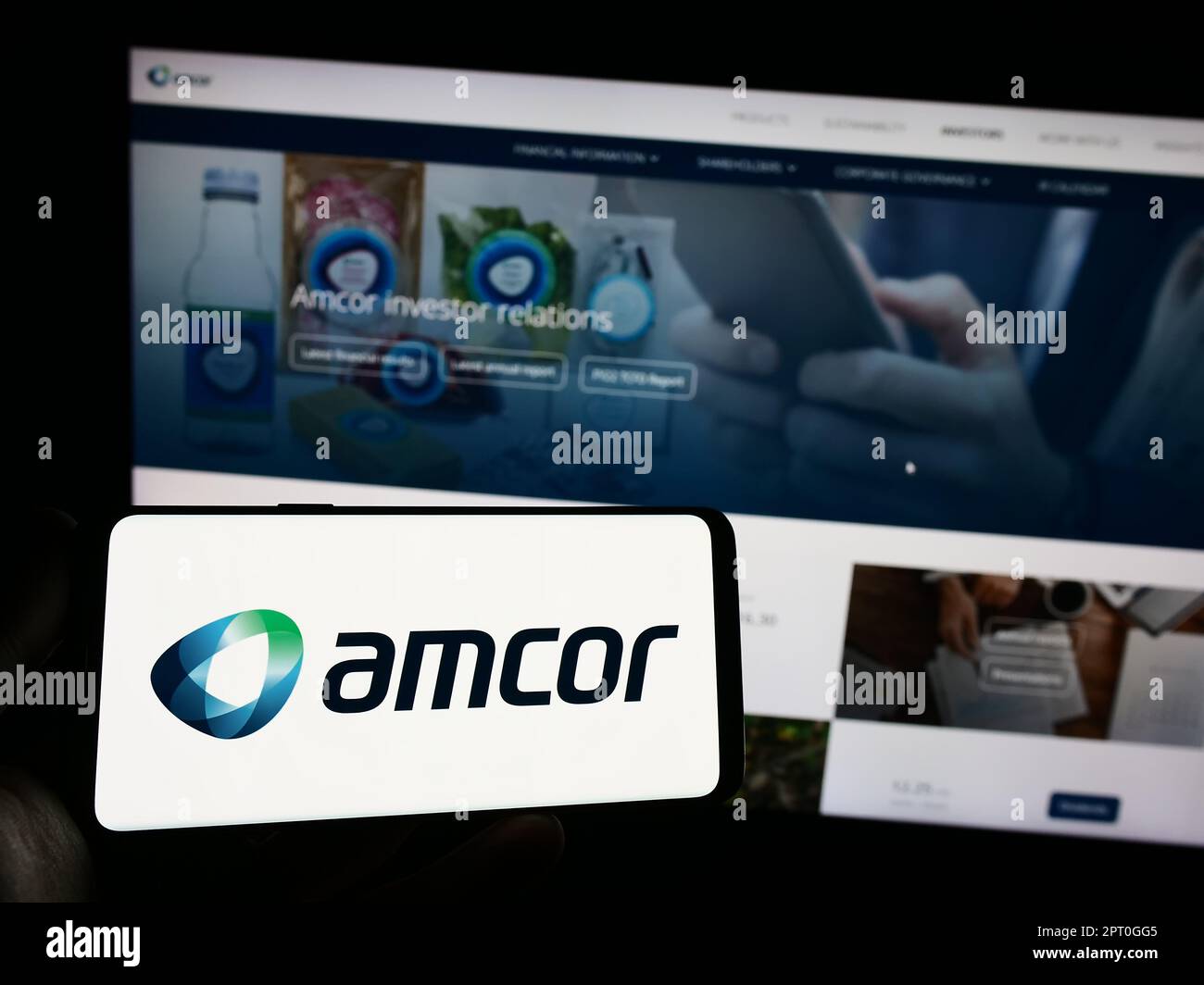 Person holding mobile phone with logo of packaging company Amcor plc on screen in front of ...