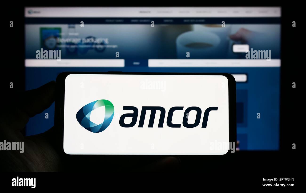 Person holding cellphone with logo of packaging company Amcor plc on screen in front of business ...