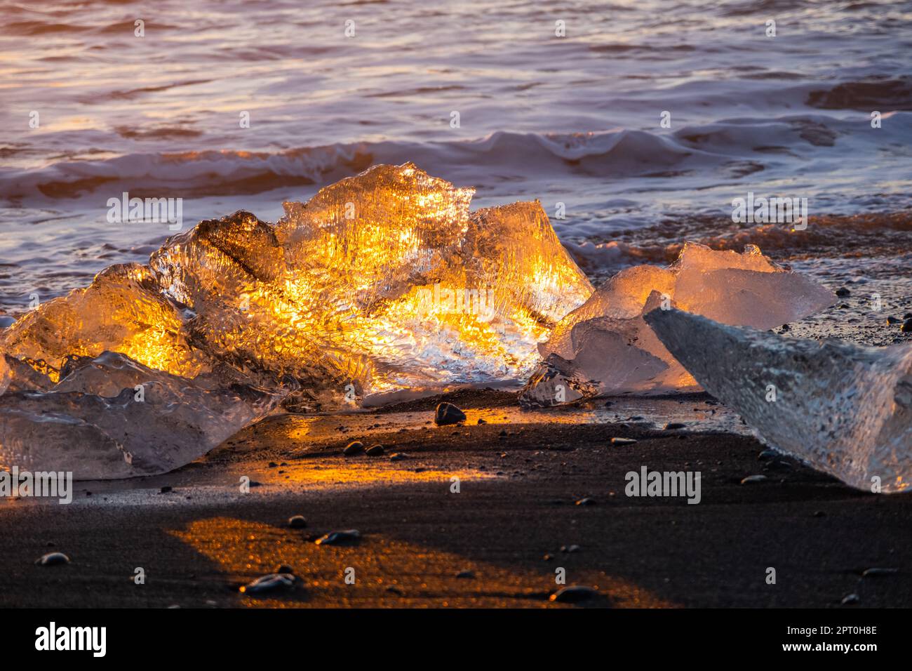 Pure Ice Shining on Black Volcanic Sand at Sunset. Icebergs from ...