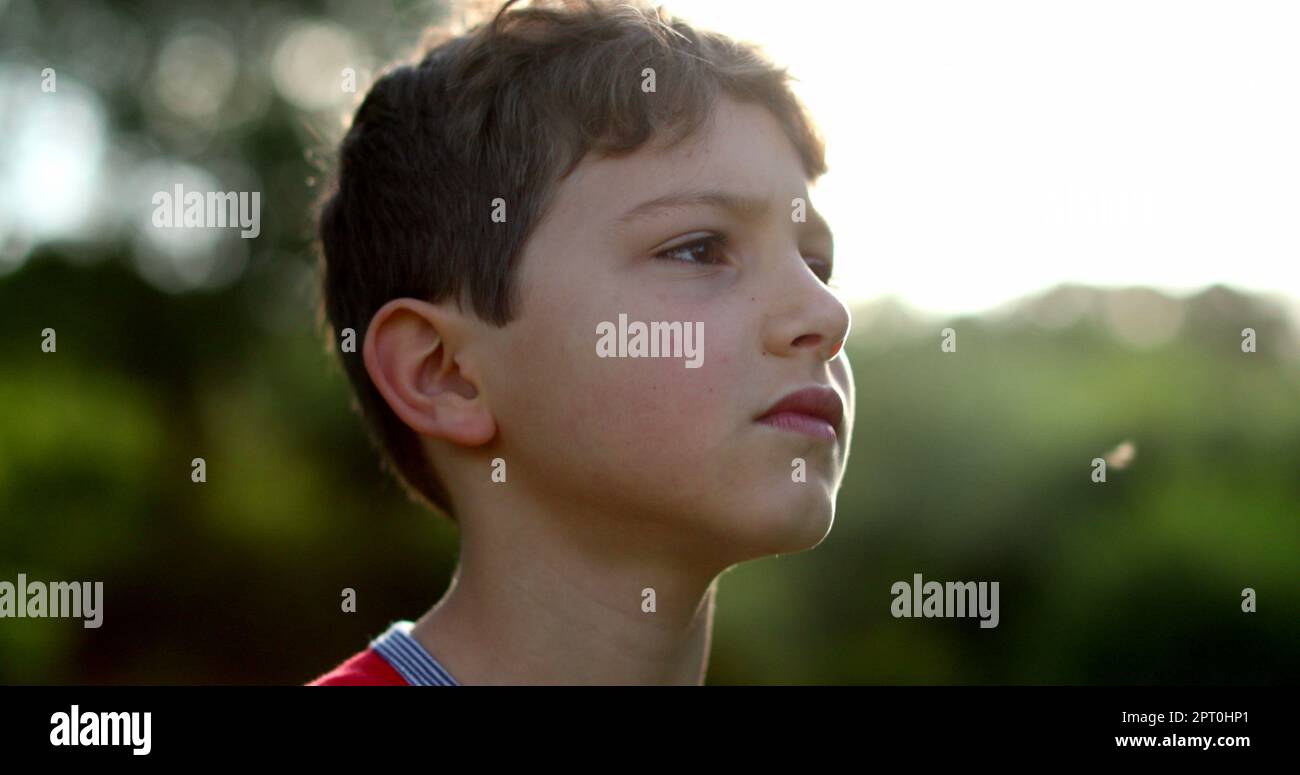 Thoughtful contemplative child looking up to the sky with hope and ...