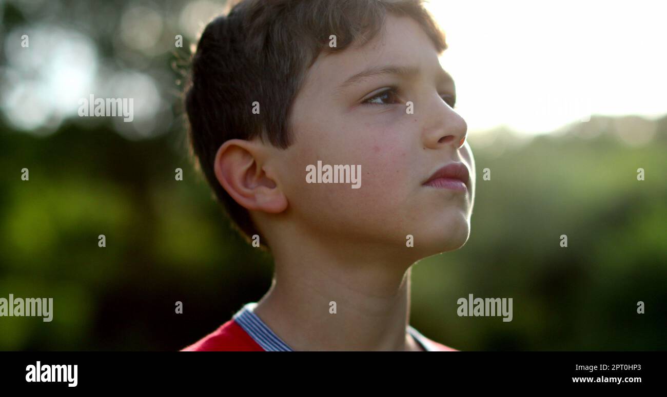 Thoughtful contemplative child looking up to the sky with hope and ...