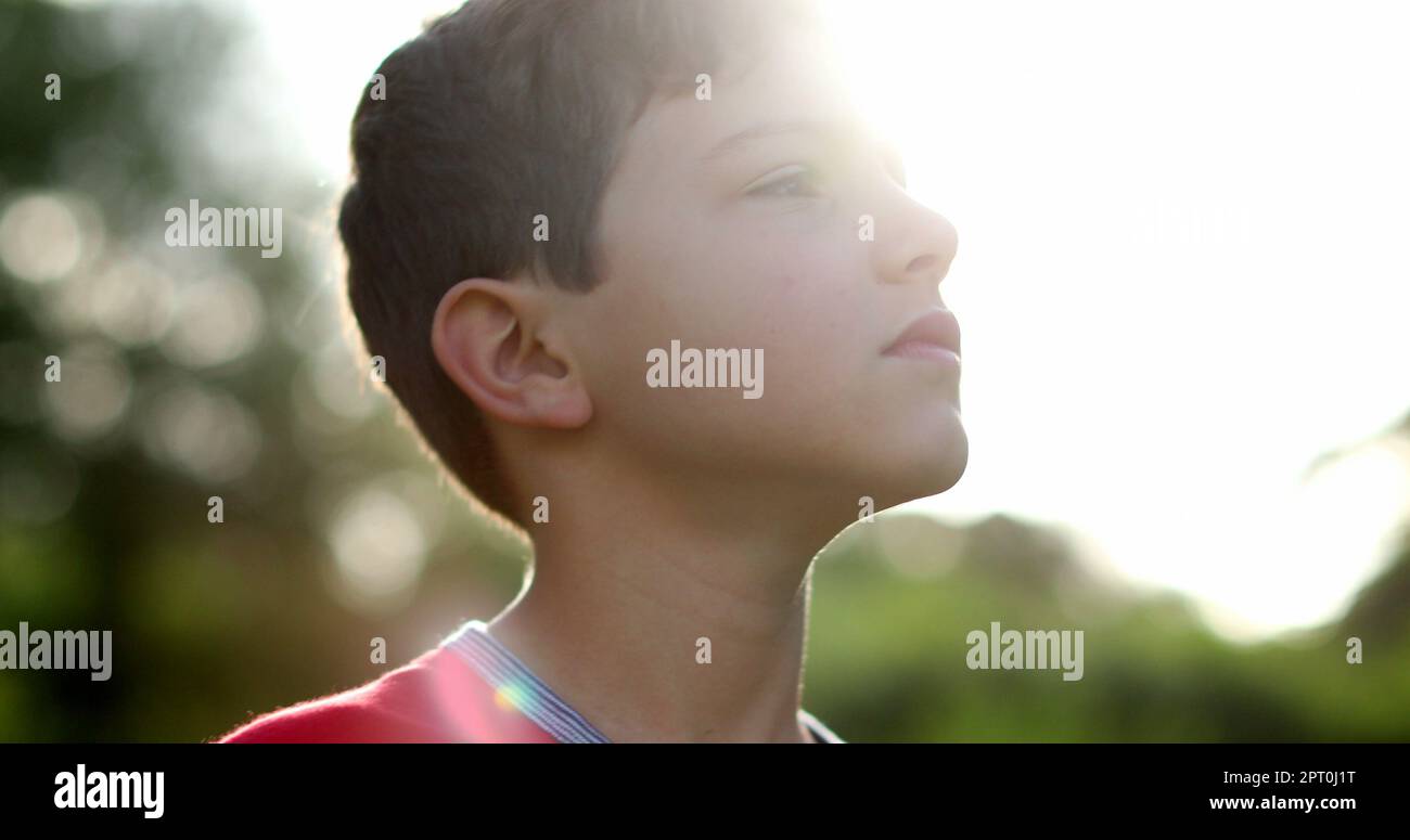 Young boy looking up to the sky with hope and faith. Thoughtful child ...