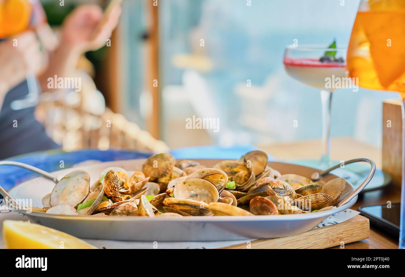 Blurred background with a dish of boiled vongole clams on a table in a ...