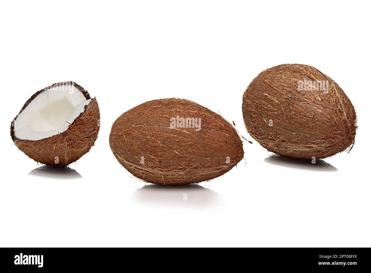 Two whole and one cut half coconuts with shadow on white background ...