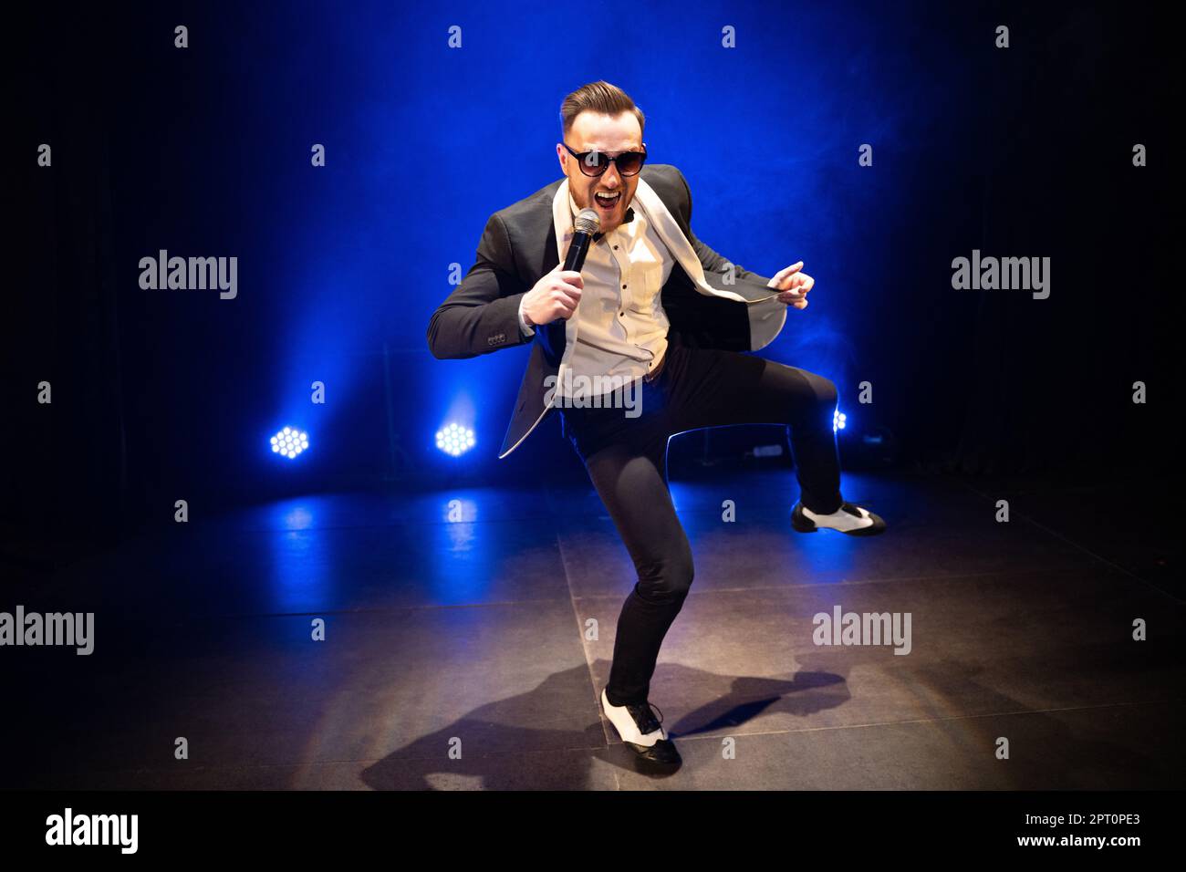 handsome presenter and showman in a stylish suit with a microphone on ...