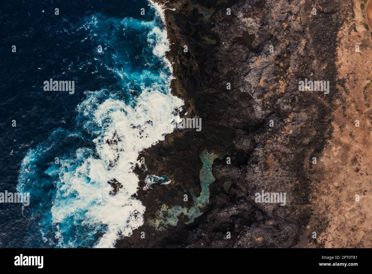 Beautiful drone shot of waves gently breaking on the shore with rocks ...