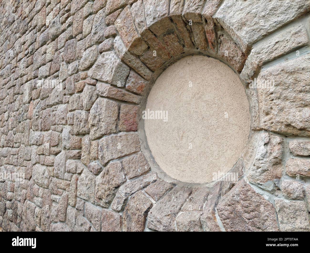 Round blind window in the stone wall of the church. background photo ...