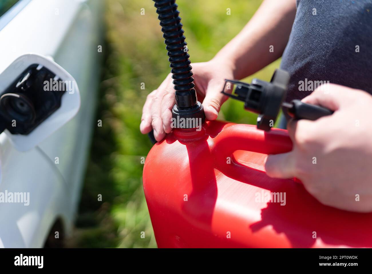 The driver refuels the empty tank of the car from a red canister on the ...